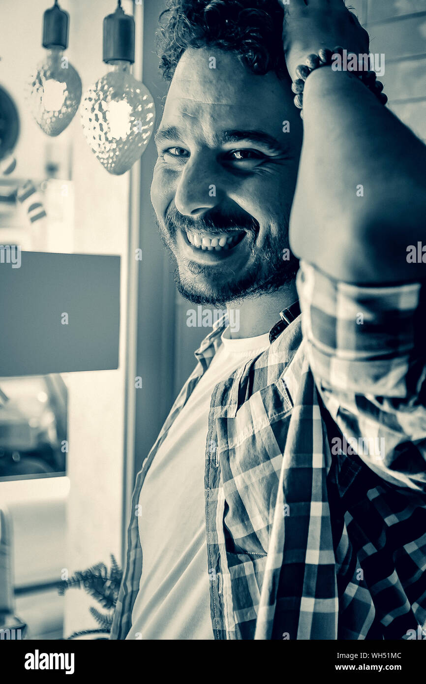 young man posing with natural light from window with carefree pose ...
