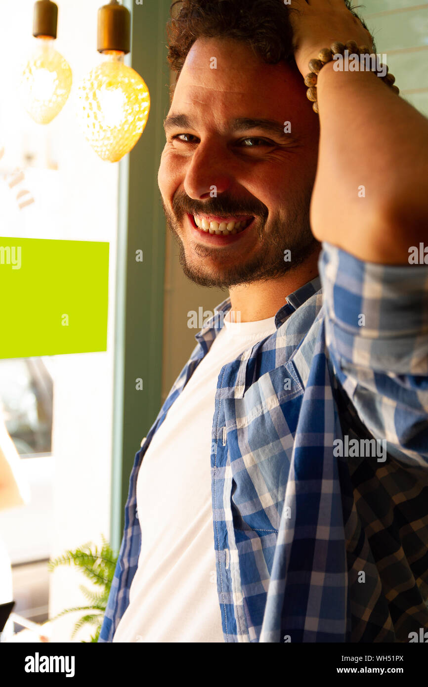 young man posing with natural light from window with carefree pose ...