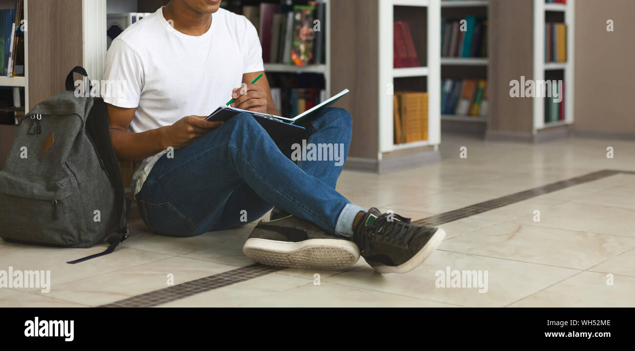 Creative male student writing essay, sitting on floor at library Stock ...