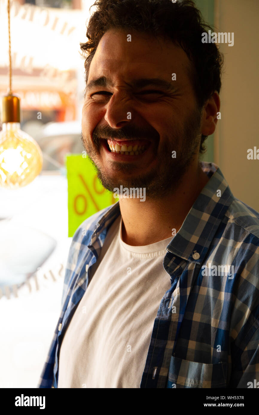 young man posing with natural light from window with casual pose while ...