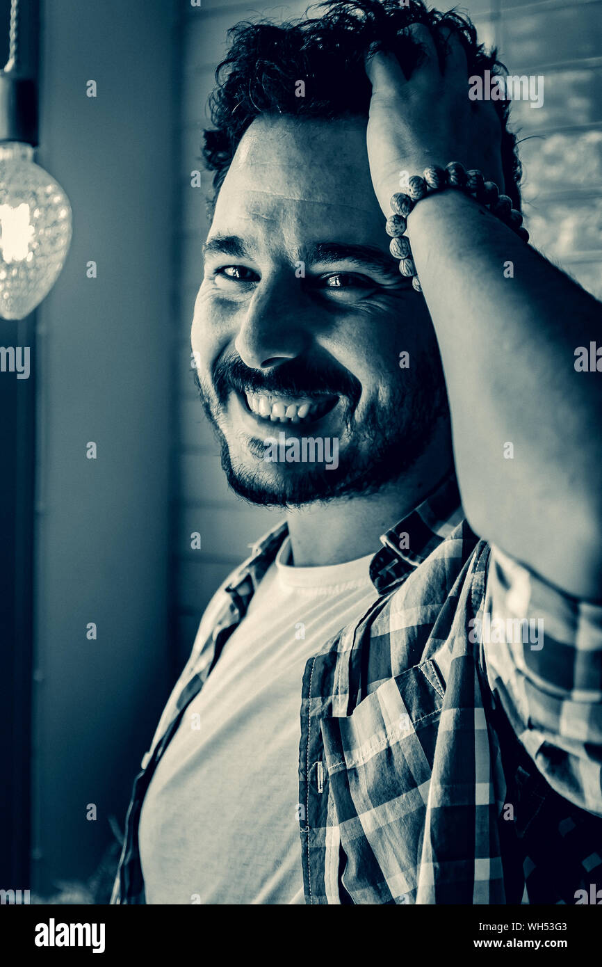 young man posing with natural light from window with carefree pose ...