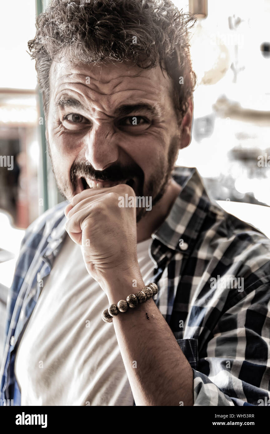 Young man biting his hand in funny pose Stock Photo - Alamy