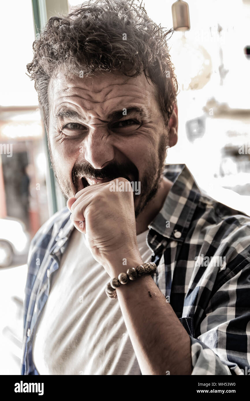 Young man biting his hand in funny pose Stock Photo - Alamy