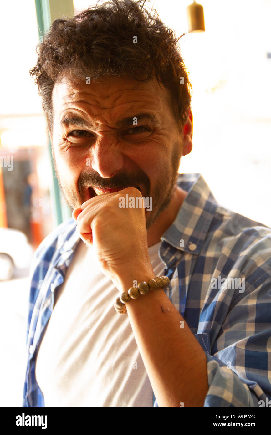 Young man biting his hand in funny pose Stock Photo - Alamy