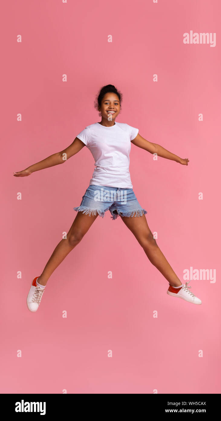 African teenage girl jumping with open hands on pink background Stock ...