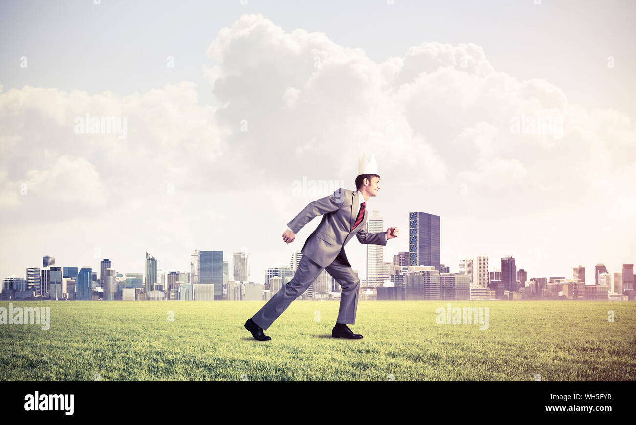 Young handsome businessman wearing white paper crown running in a hurry ...