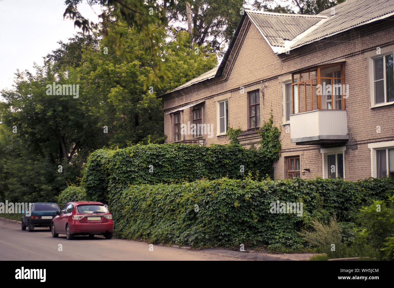 Old tenement house with green fence on summer street in Russia Stock ...