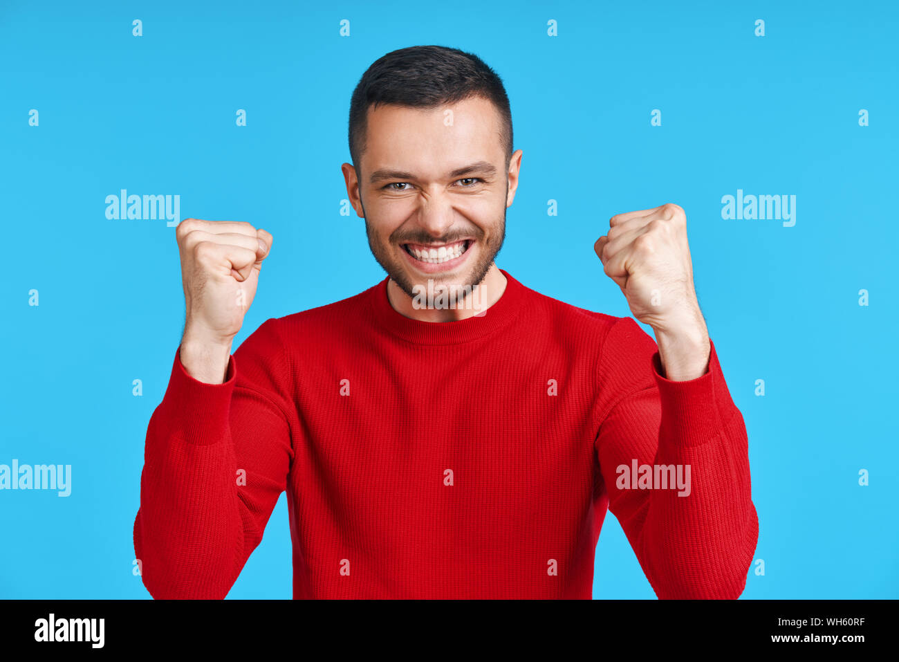 Happy man celebrating his success with winner gesture on blue ...