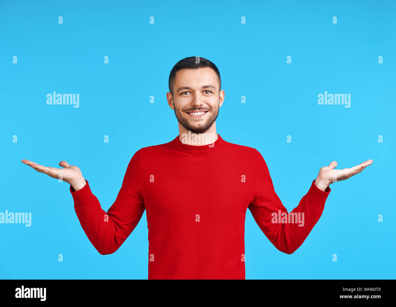 Handsome happy man presenting copy space isolated on blue background ...