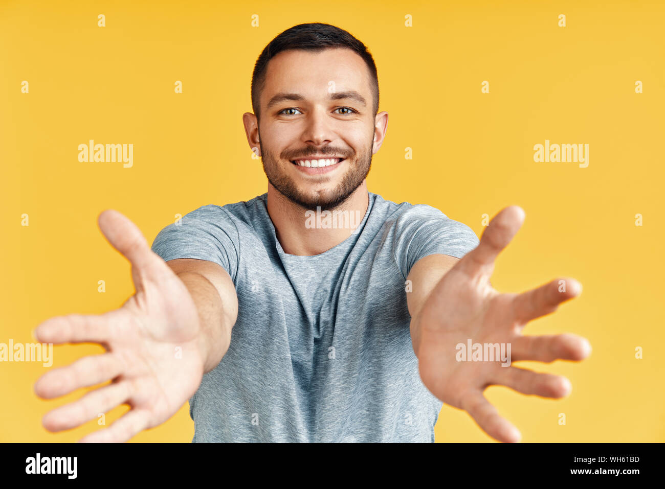 Handsome happy man with open hand ready for hugs on yellow background ...