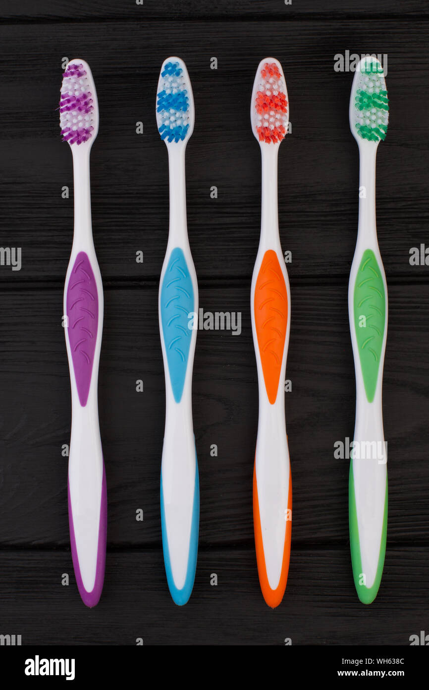 Four colorful toothbrushes on black background Stock Photo - Alamy