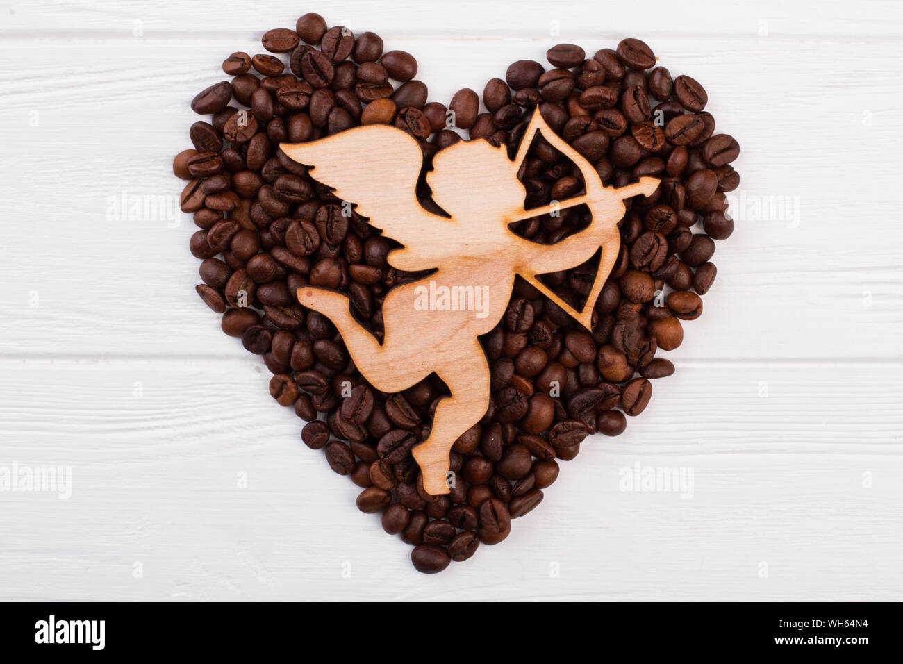 Roasted coffee beans in a shape of heart and wooden cupid Stock Photo ...