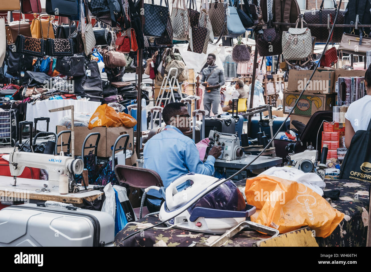 London, UK - July 18, 2019: Trader tailoring clothes at a stall on ...