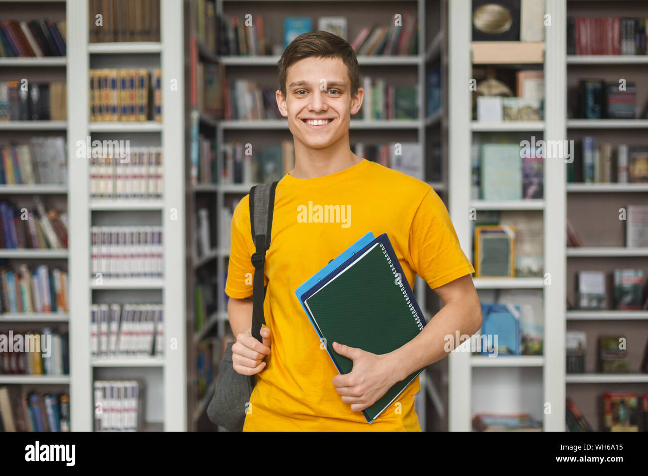 Handsome young guy standing in library, bookshelves background Stock ...