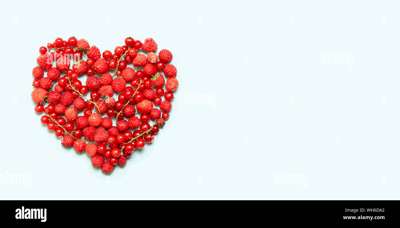 Various fresh summer berries in heart shapeon pink background. Summer ...