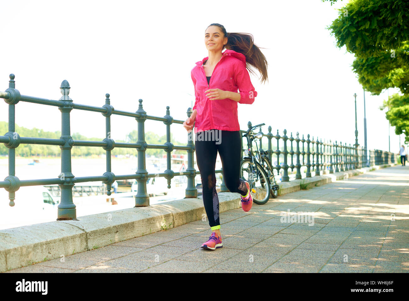 Full length shot of young woman wearing sportwear while running on the ...