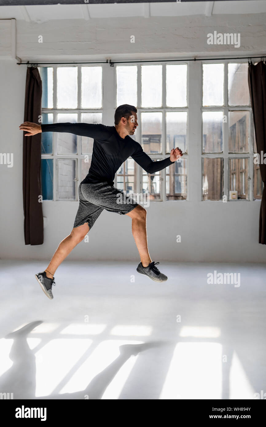 Dynamic athlete jumping in studio loft Stock Photo - Alamy