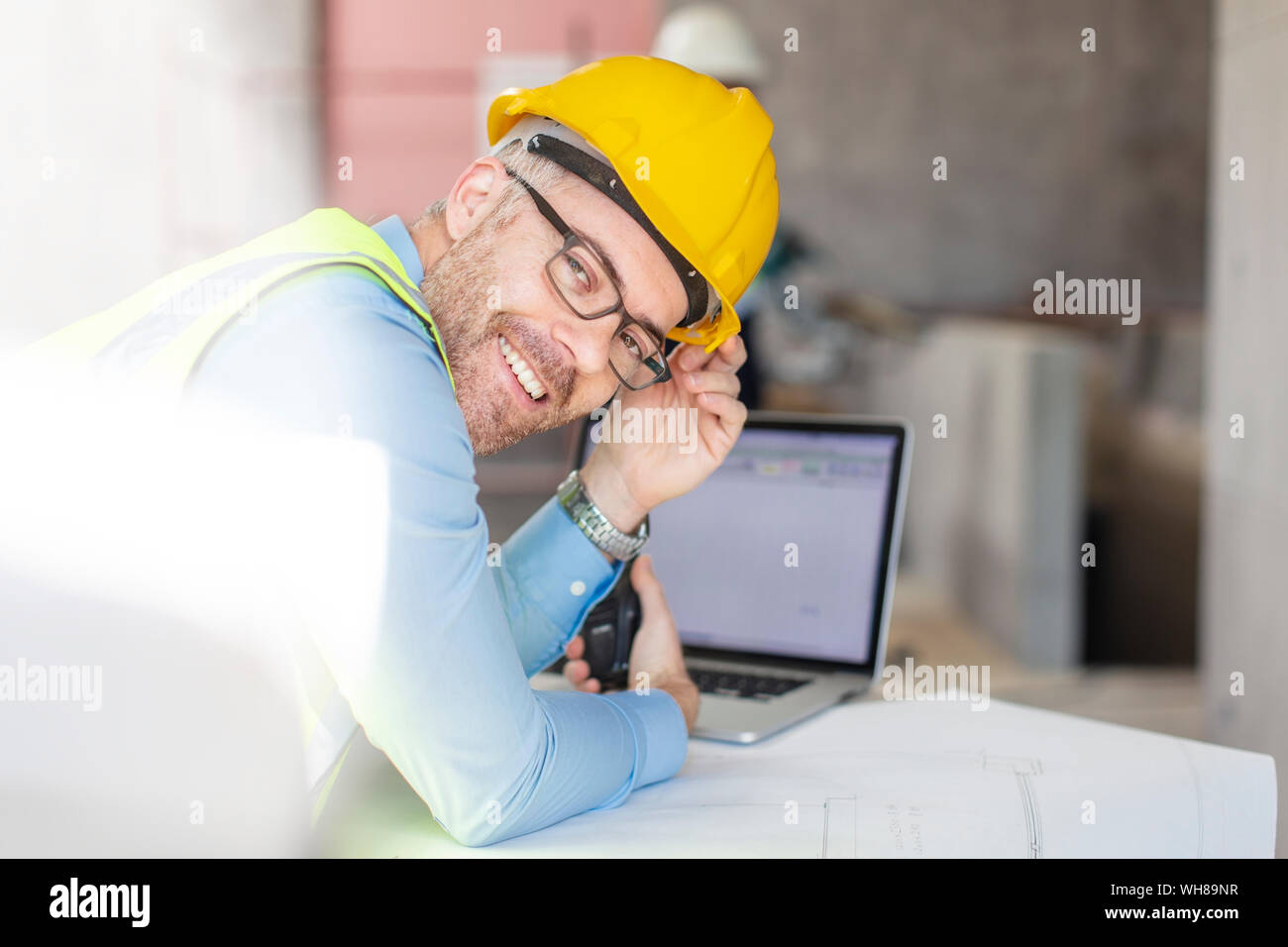 Architect using laptop at construction site, looking at camera Stock ...