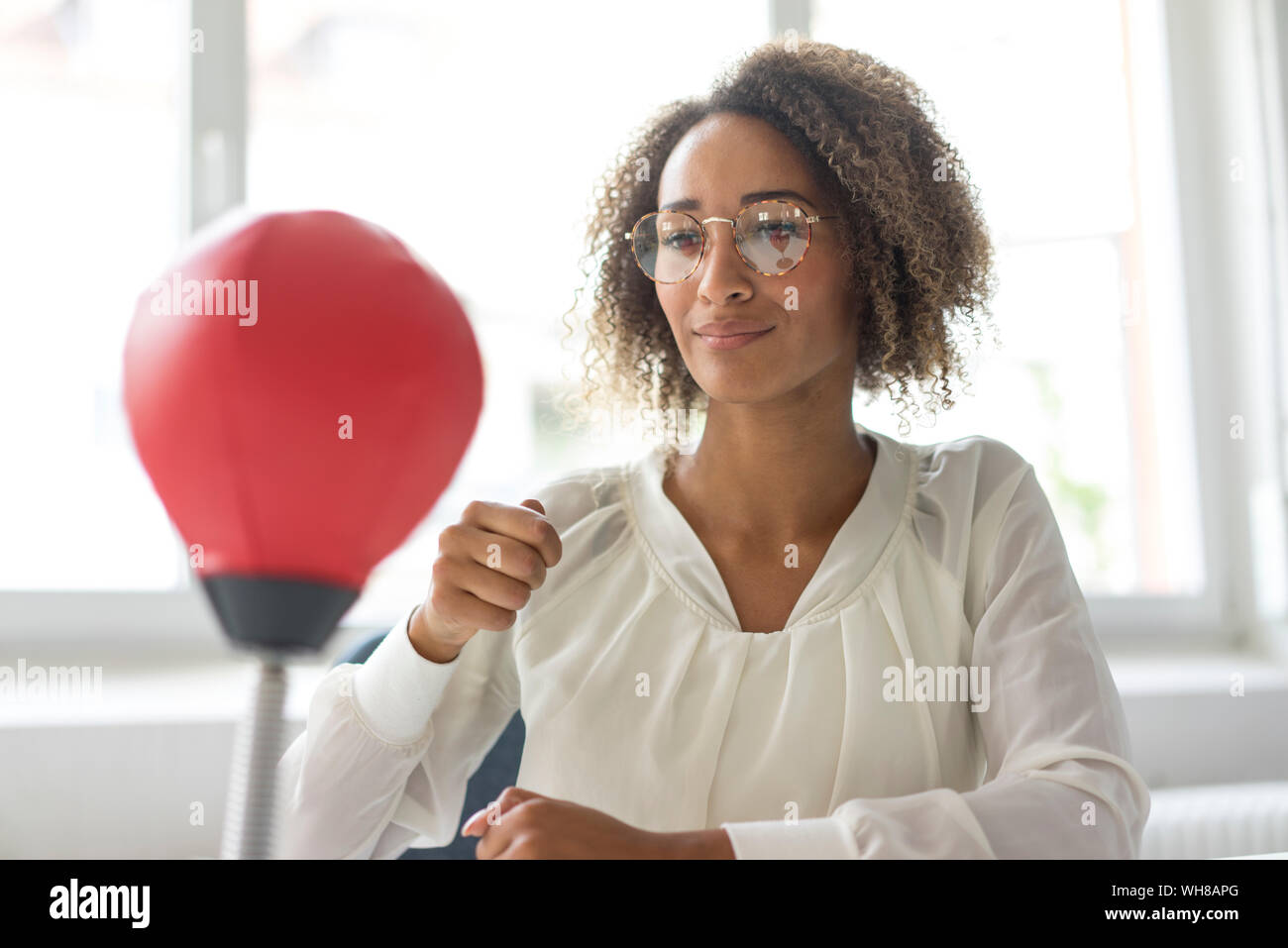 Portrait of young freelancer sitting at desk in office boxing punching ...