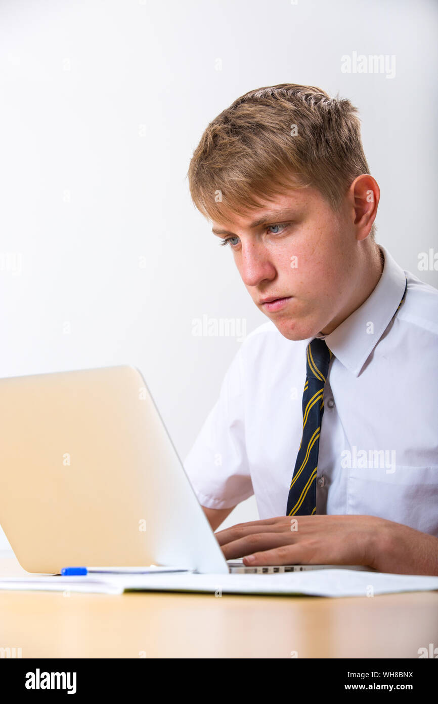 A teenage school boy in uniform working on a laptop computer Stock ...