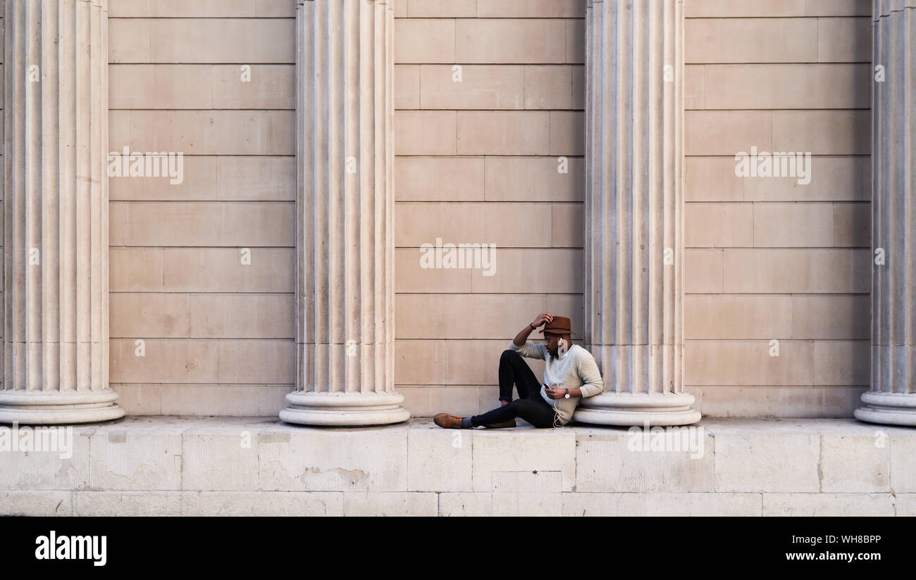Mid adult man sitting between columns Stock Photo - Alamy