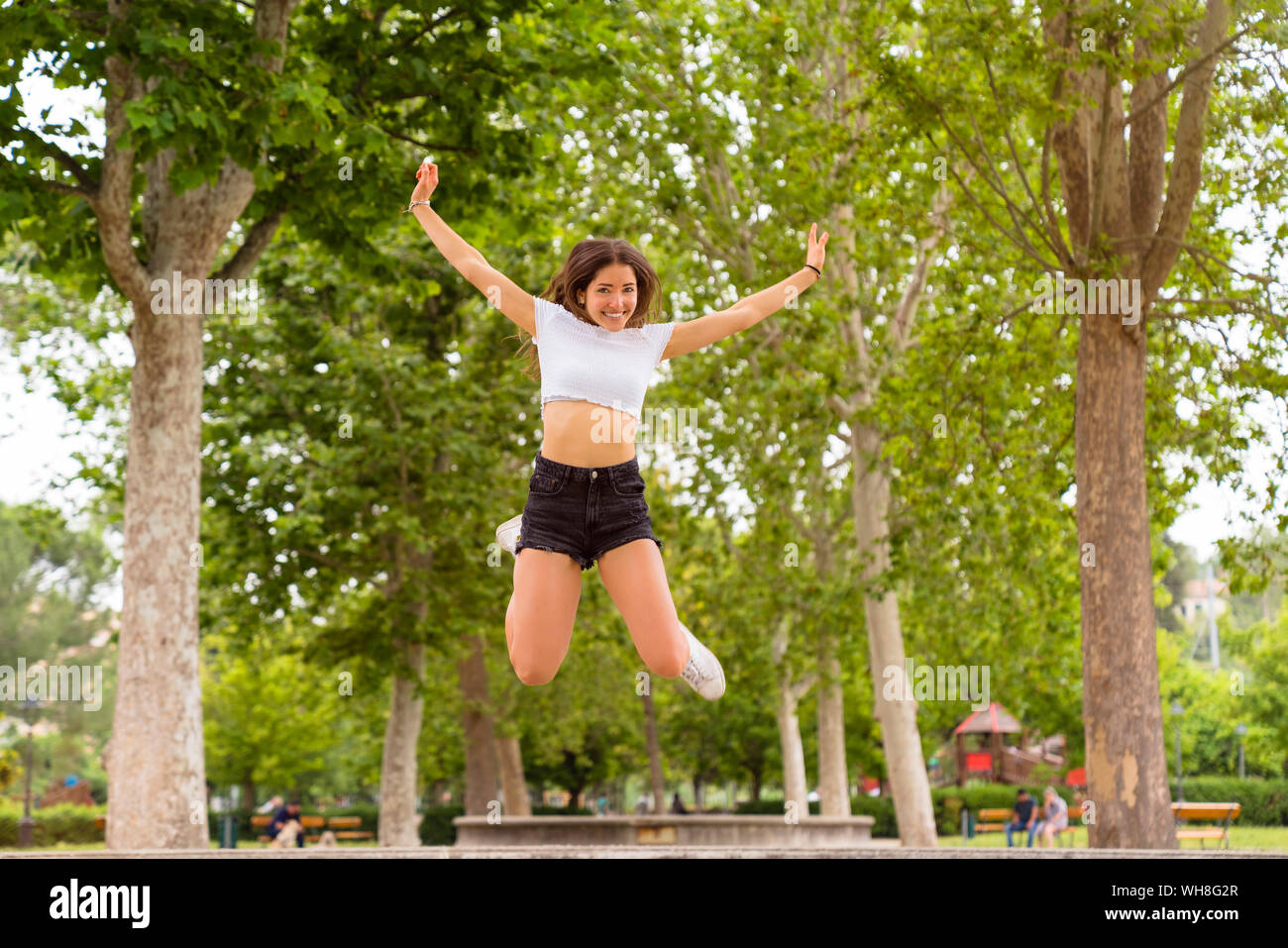 Young woman jumping in park Stock Photo - Alamy