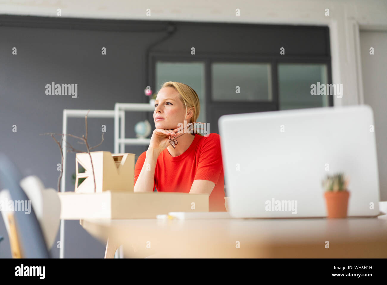 Young woman in office thinking with architectural model on desk Stock ...
