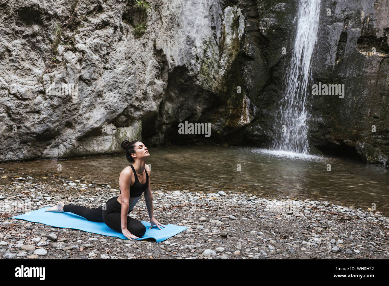 Woman practising yoga at waterfall, cobra pose Stock Photo - Alamy