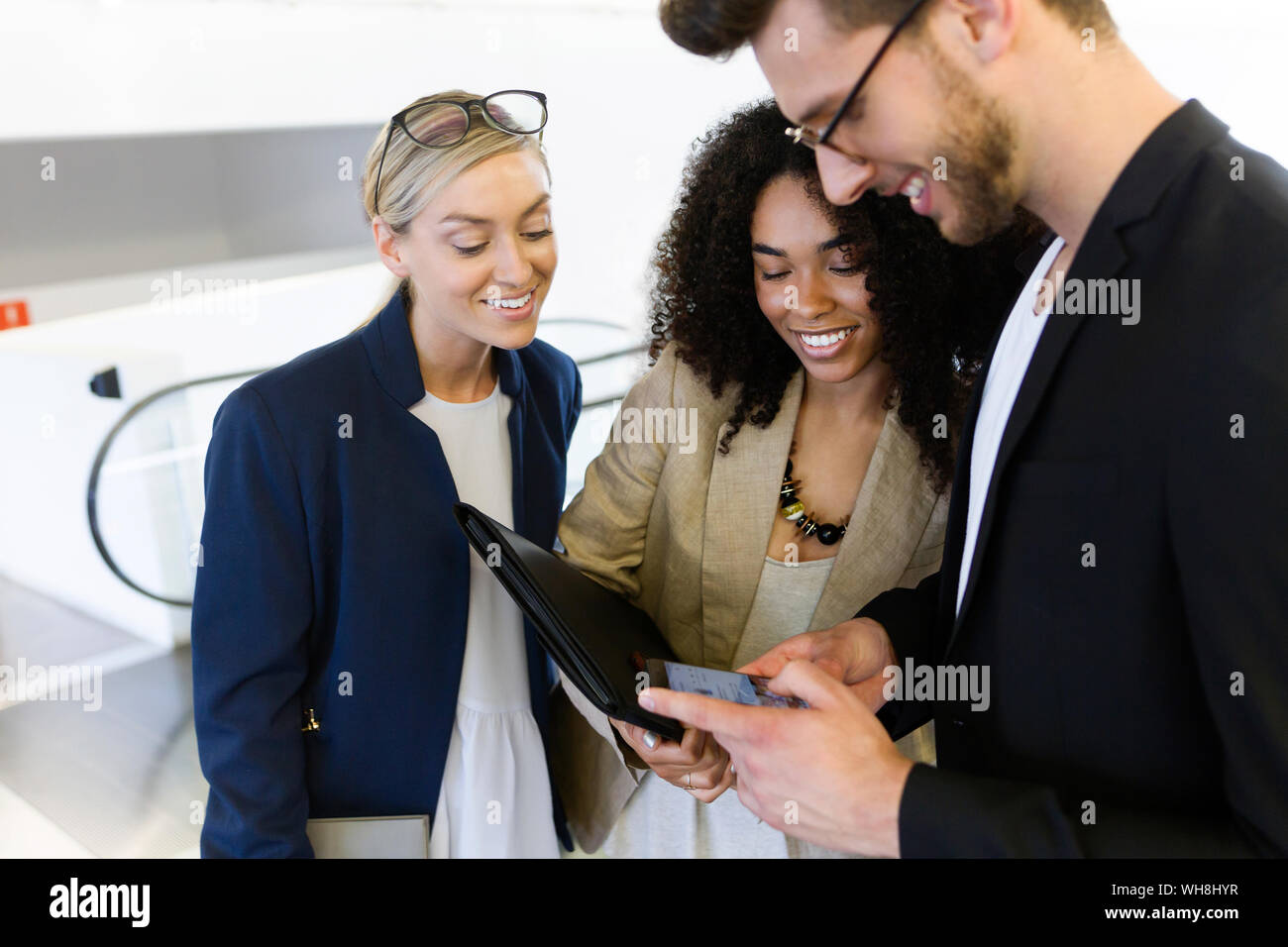 Three young business people sharing a smartphone Stock Photo - Alamy