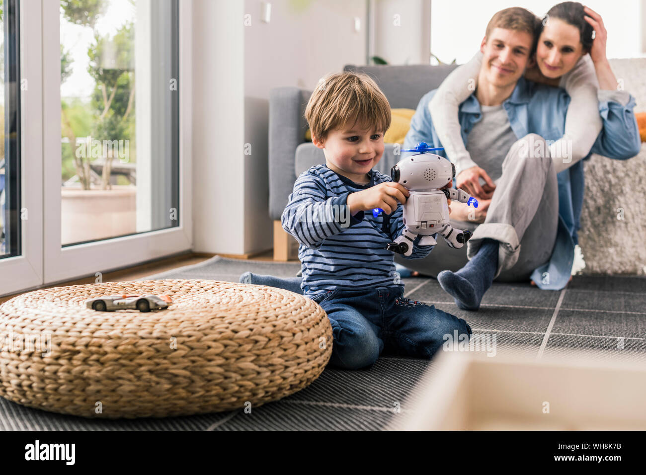 Parents watching son, playing with toy robot Stock Photo - Alamy