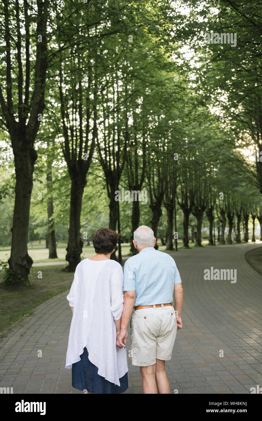 Back view of senior couple strolling hand in hand in a park Stock Photo ...