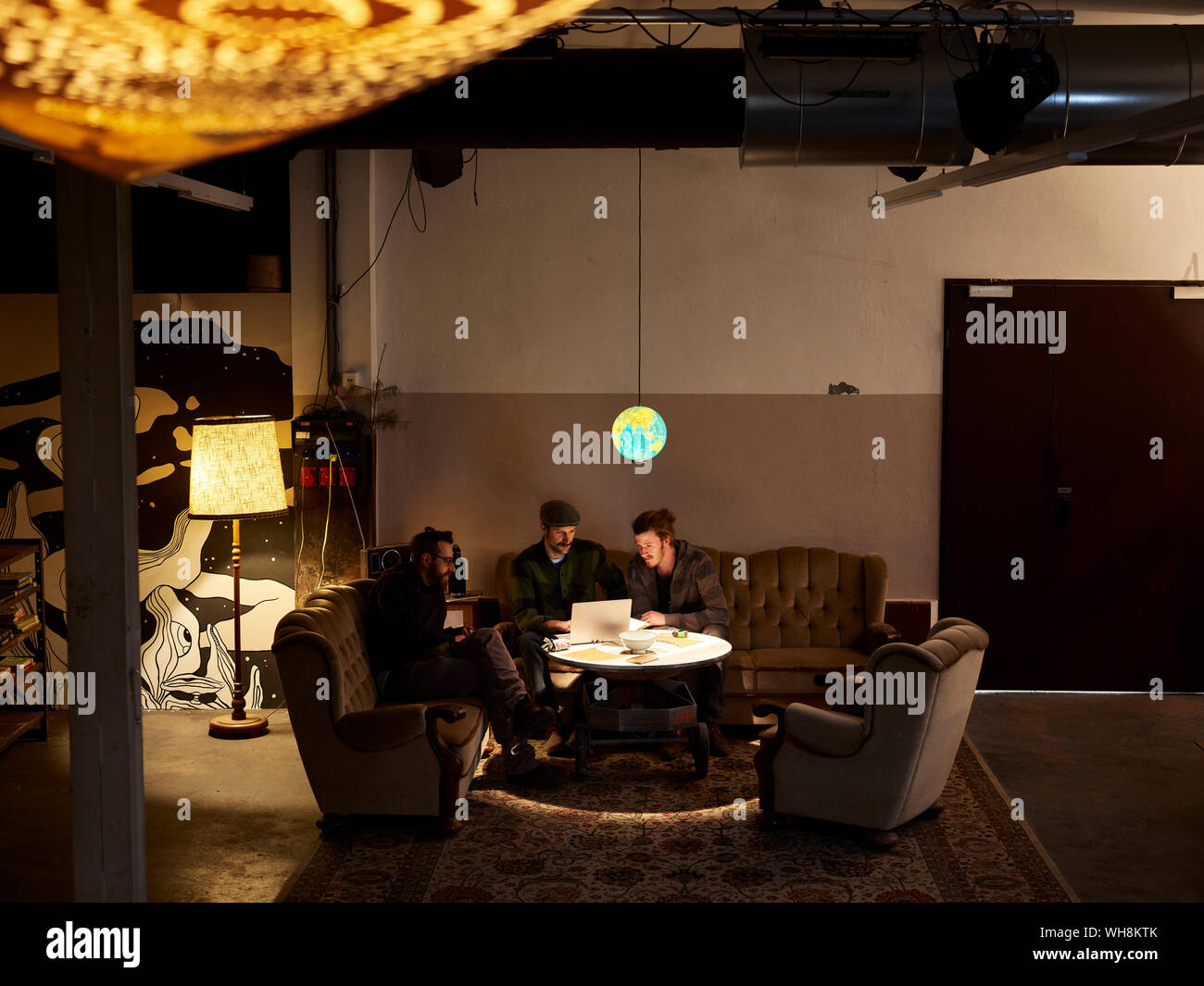 Three men using laptop in a loft Stock Photo - Alamy