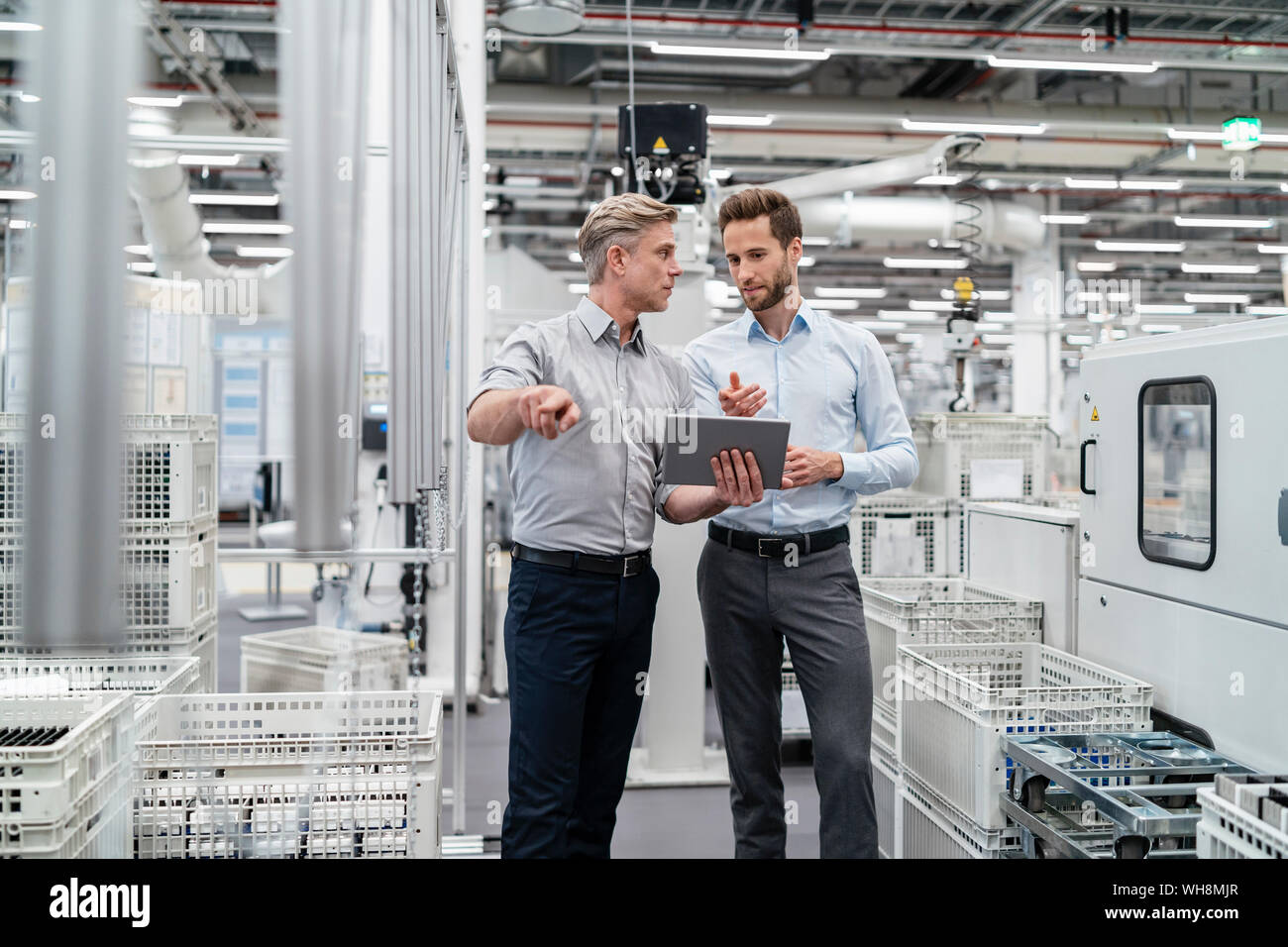 Two businessmen with tablet talking in a modern factory Stock Photo - Alamy
