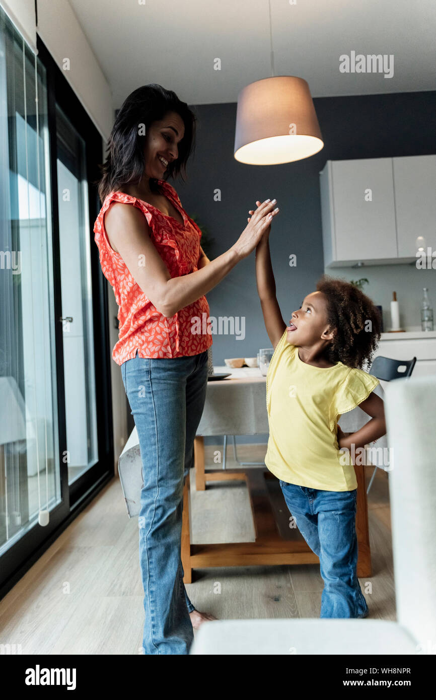 Happy mother and daughter high fiving in kitchen Stock Photo - Alamy