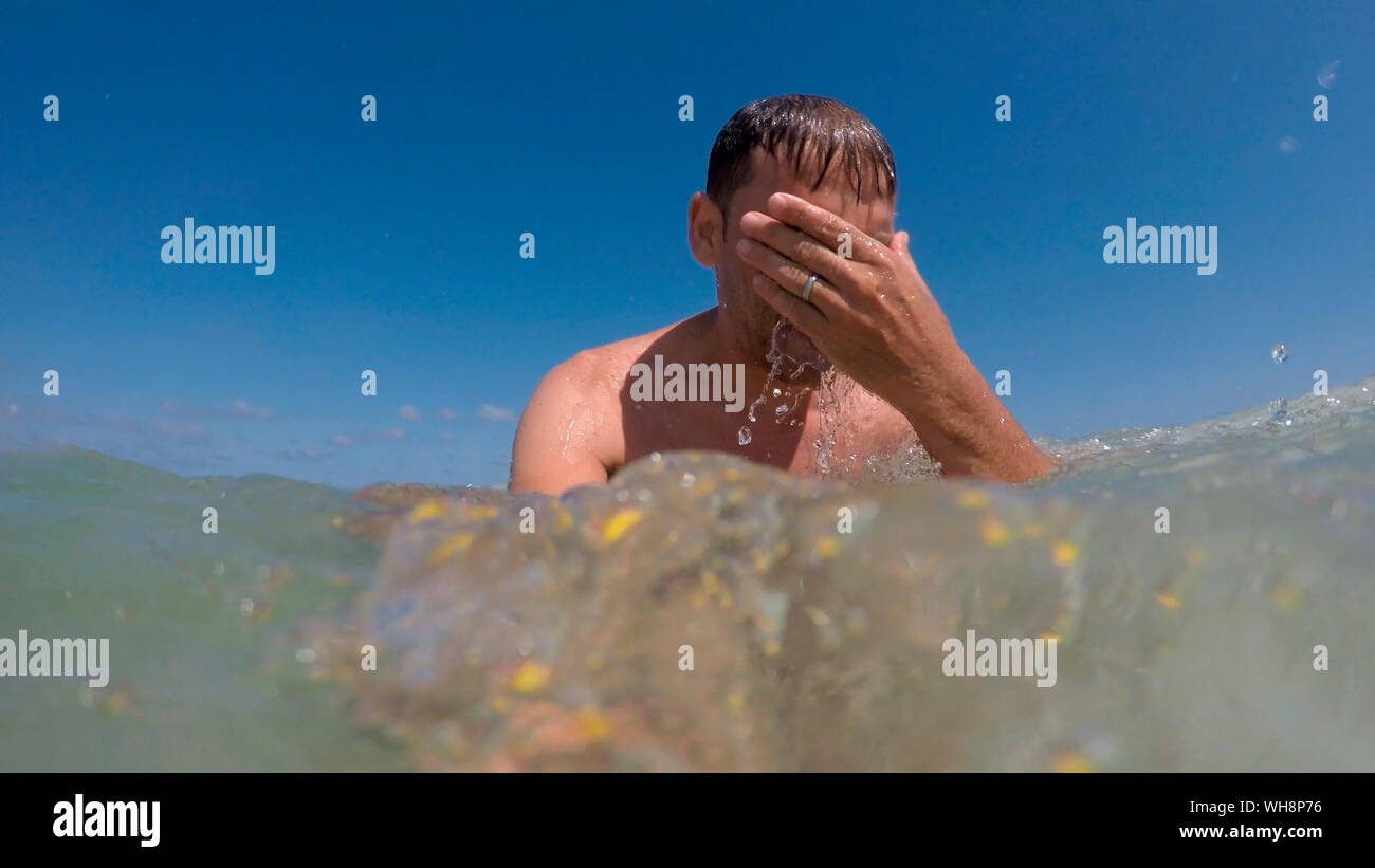 Man shipwreck amidst the waves of the sea, he has his hand on his face ...