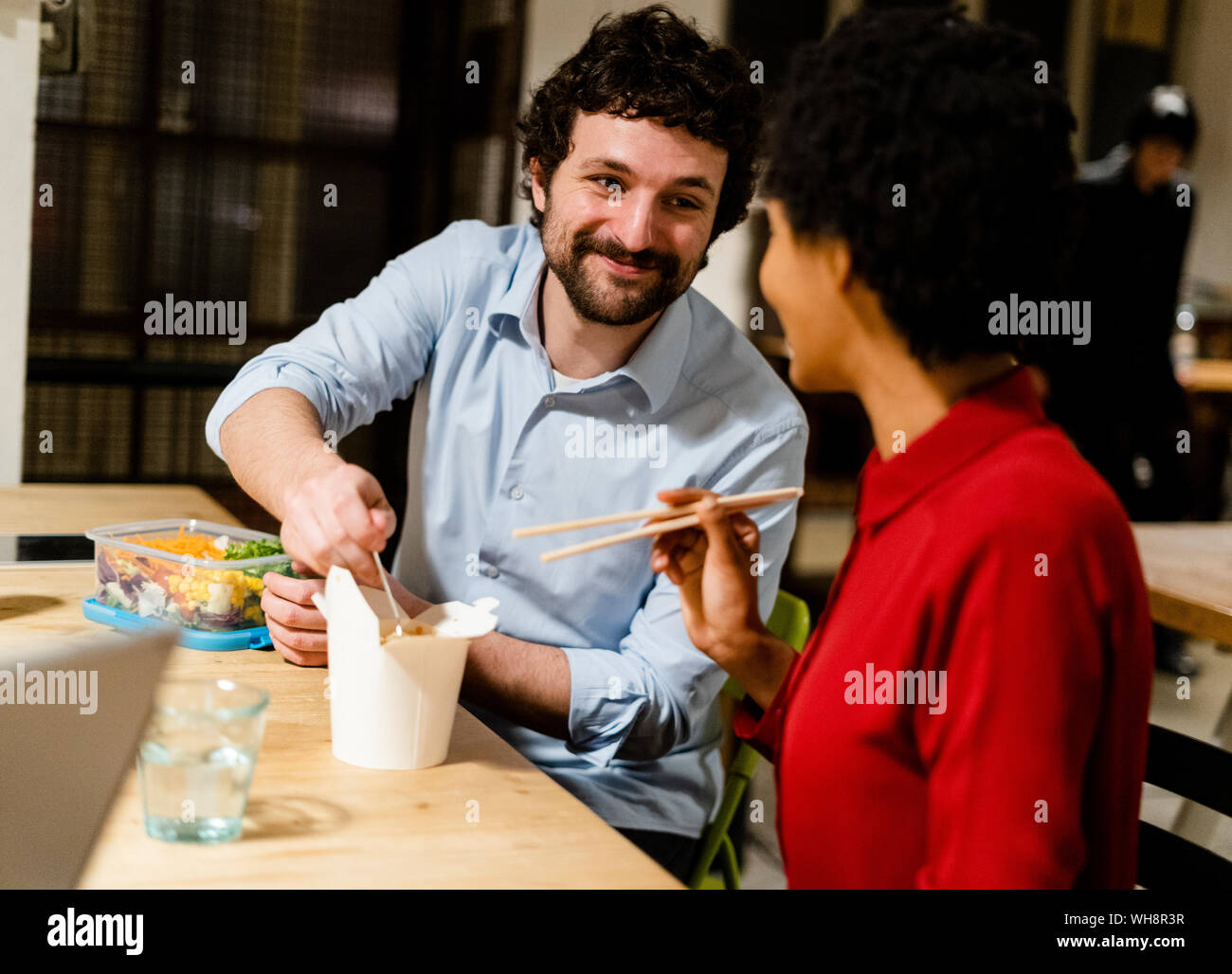 Colleagues in office having lunch break sharing Chinese takeout food ...