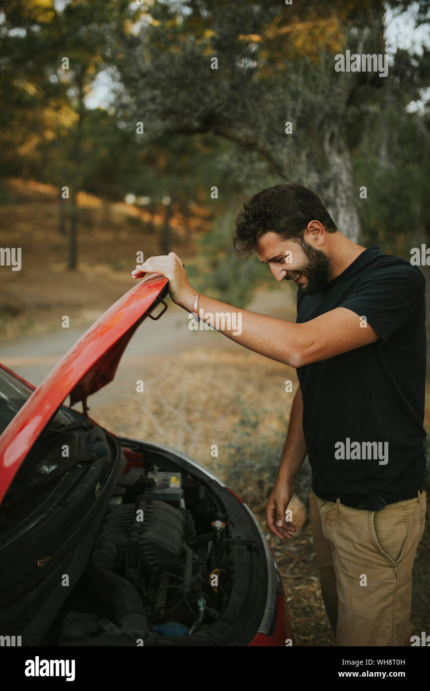 Man standing at car, looking at engine Stock Photo - Alamy