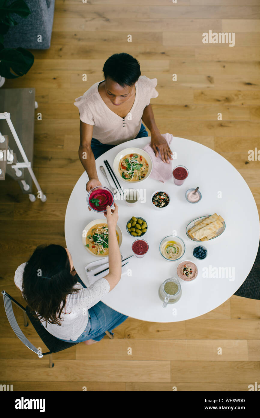 Two women sitting at table having a healthy meal Stock Photo - Alamy