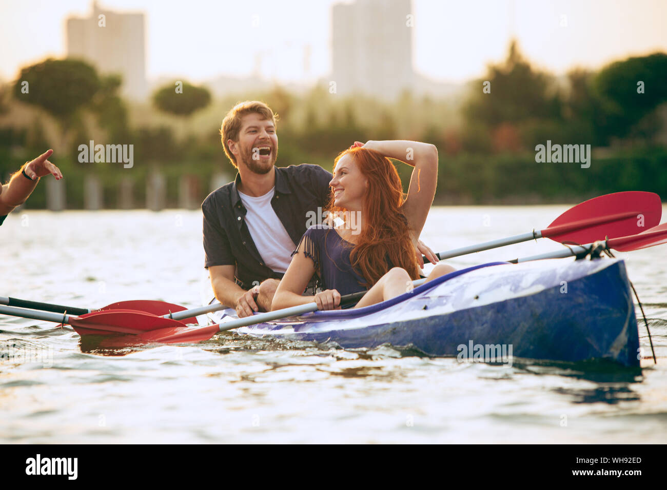 Confident young caucasian couple kayaking on river together with sunset ...