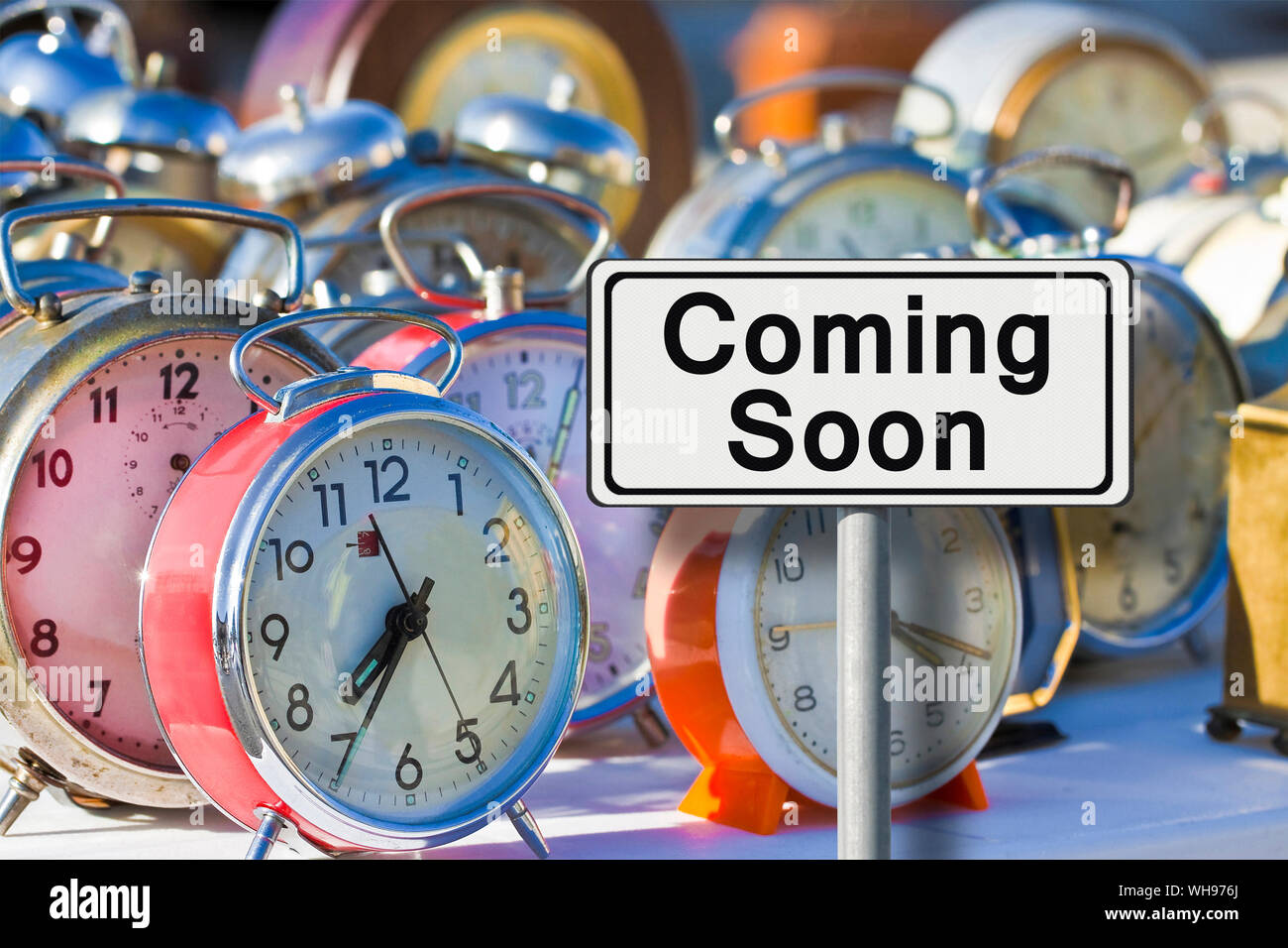 Coming soon sign - concept image with old colored metal table clocks ...