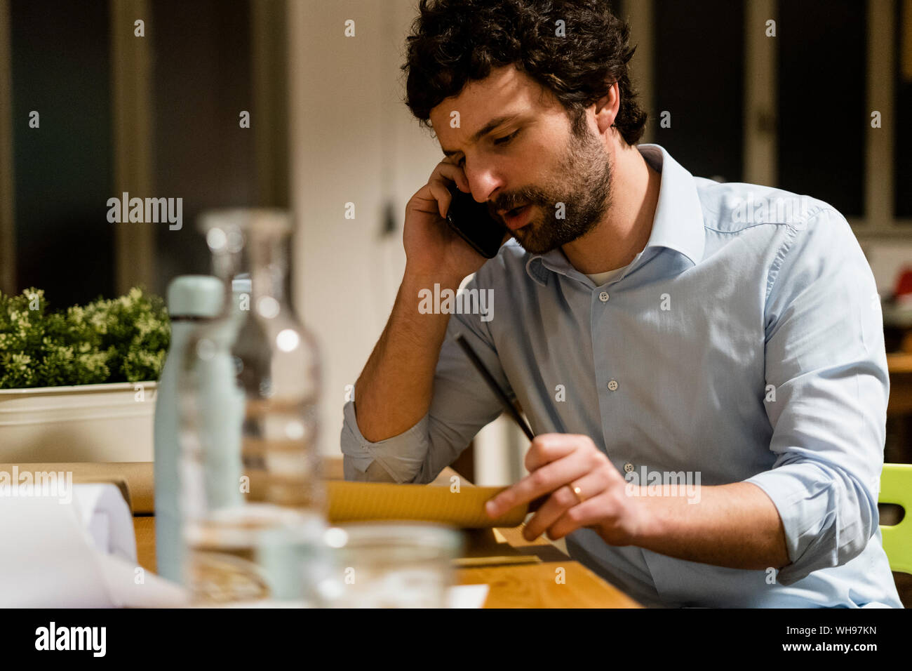 Businessman talking on cell phone at desk in office Stock Photo - Alamy