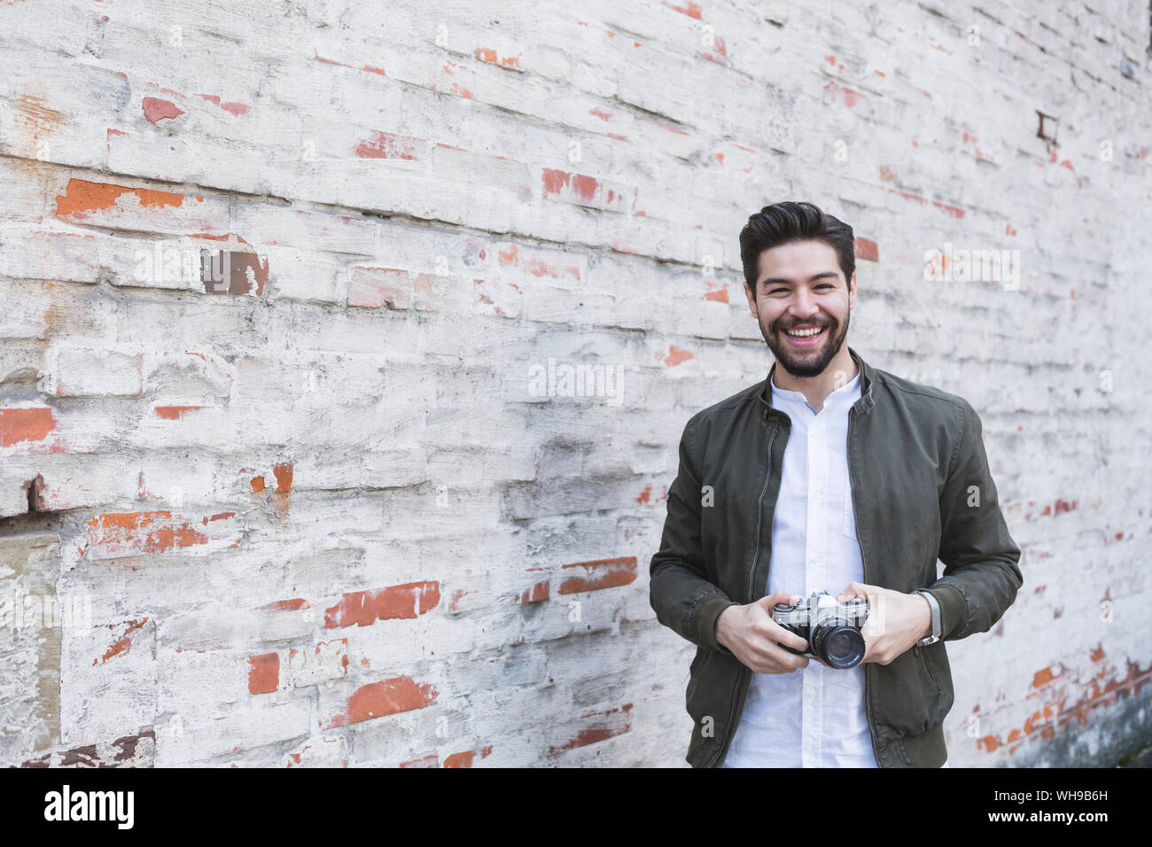 Portrait of laughing young man with camera Stock Photo - Alamy