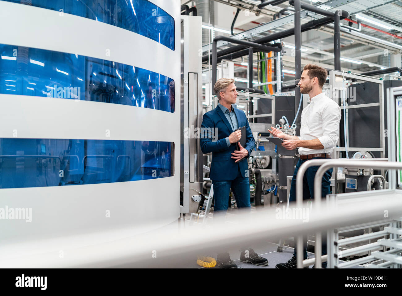 Two businessmen talking in a modern factory Stock Photo - Alamy