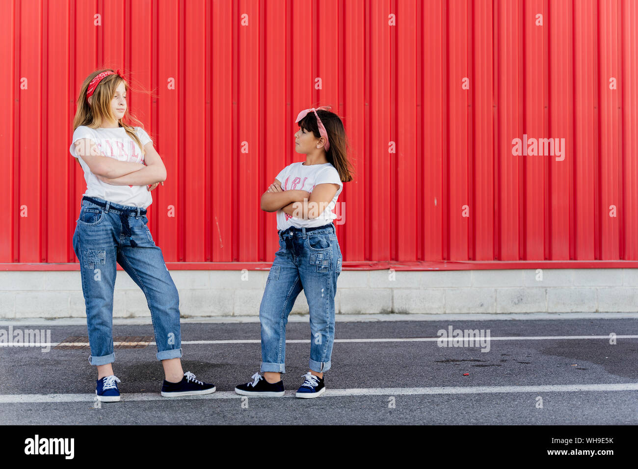 Sisters with arms crossed standing in front of a red wall Stock Photo ...