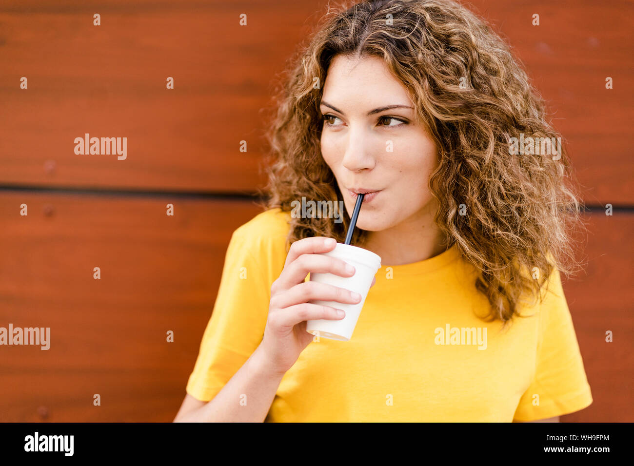 Young woman drinking from disposable cup looking sideways Stock Photo ...