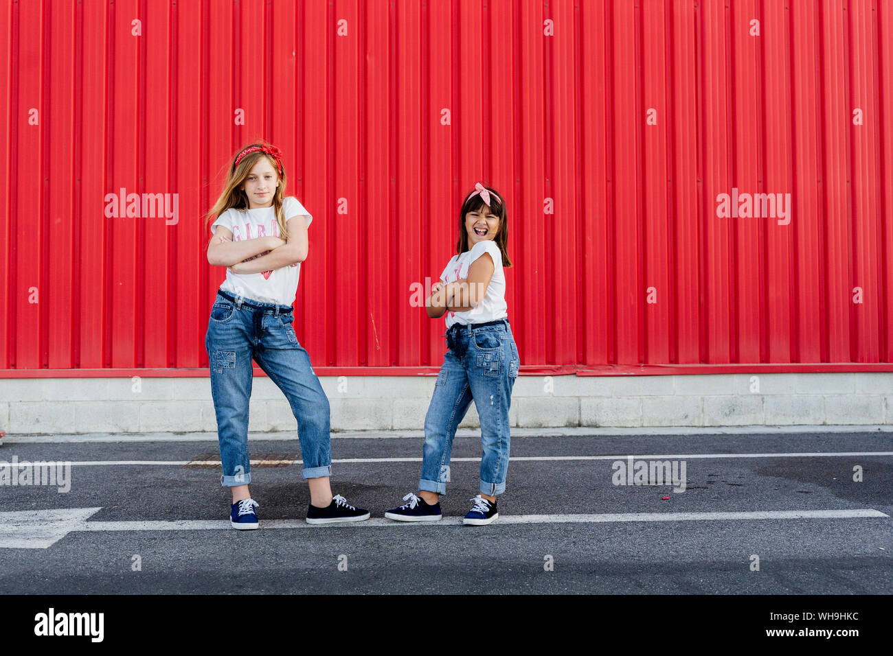Sisters with arms crossed standing in front of a red wall Stock Photo ...