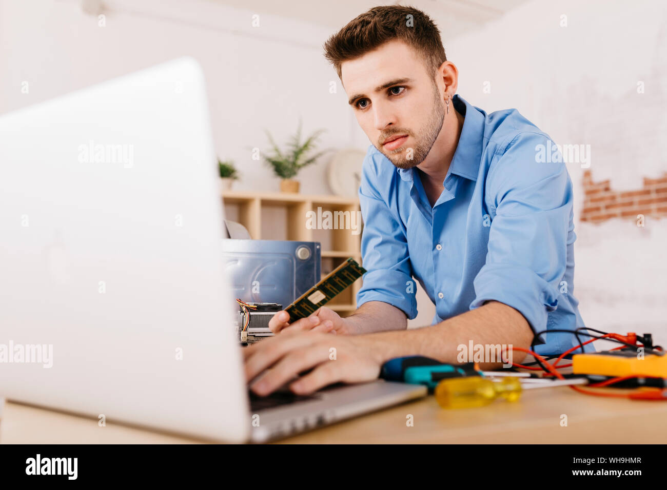 Technician repairing a desktop computer, using laptop Stock Photo - Alamy