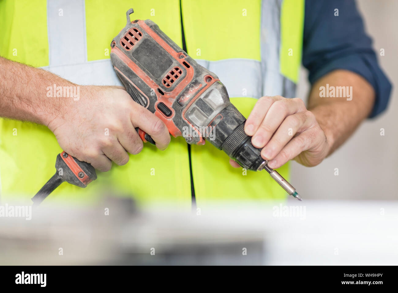 Worker holding drill Stock Photo - Alamy