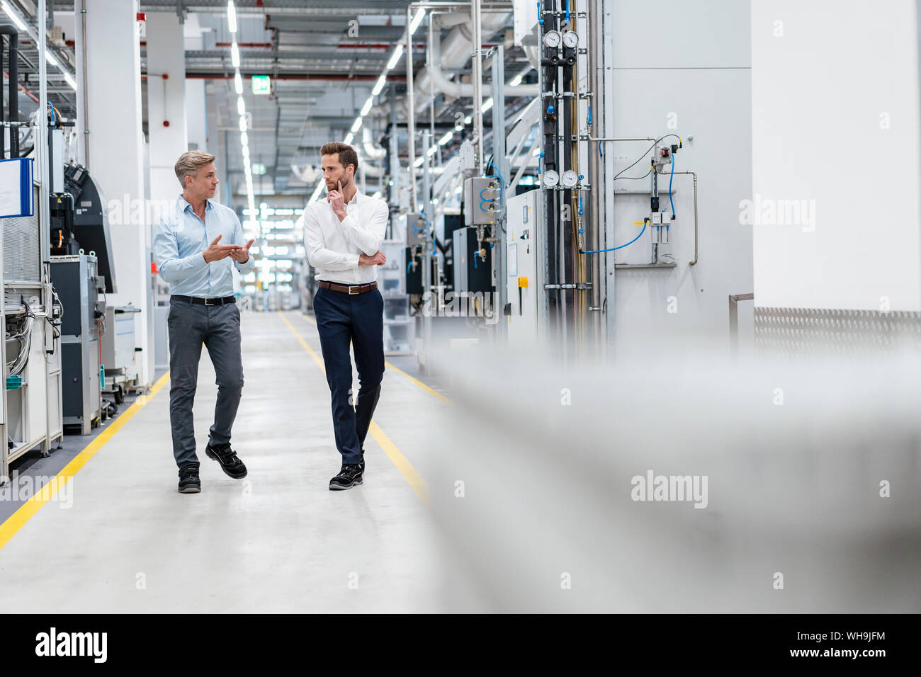 Two businessmen talking in a modern factory Stock Photo - Alamy