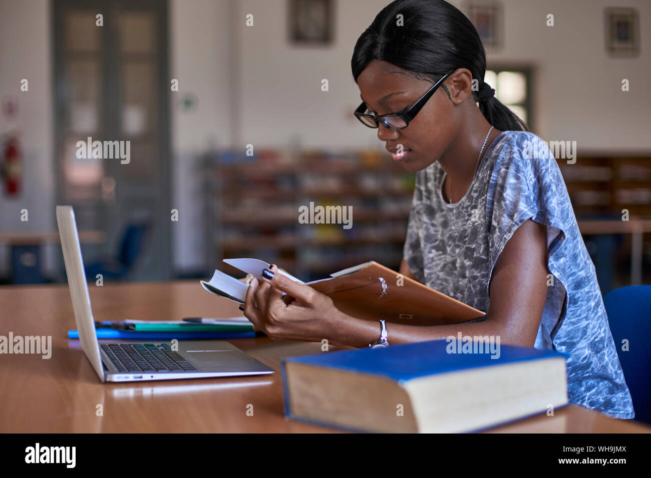 Young student with laptop reading a book at National library, Maputo ...